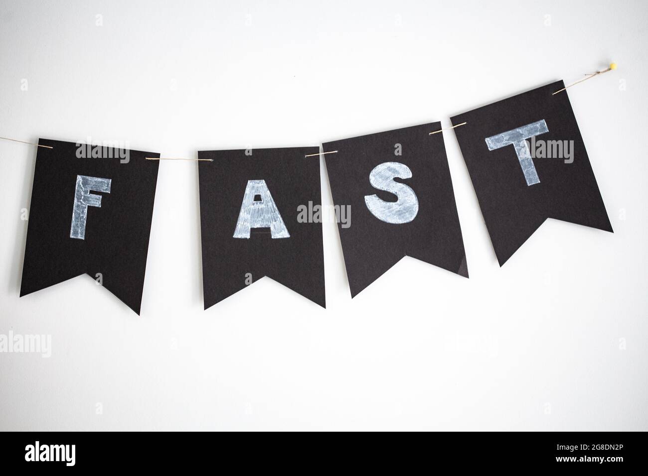 Fast word letters written on black flags on a white wall background ...