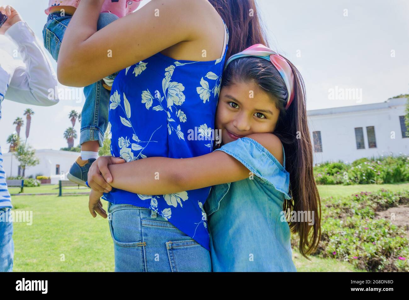 Cute pretty Hispanic girl hugging her mother from her back Stock Photo ...