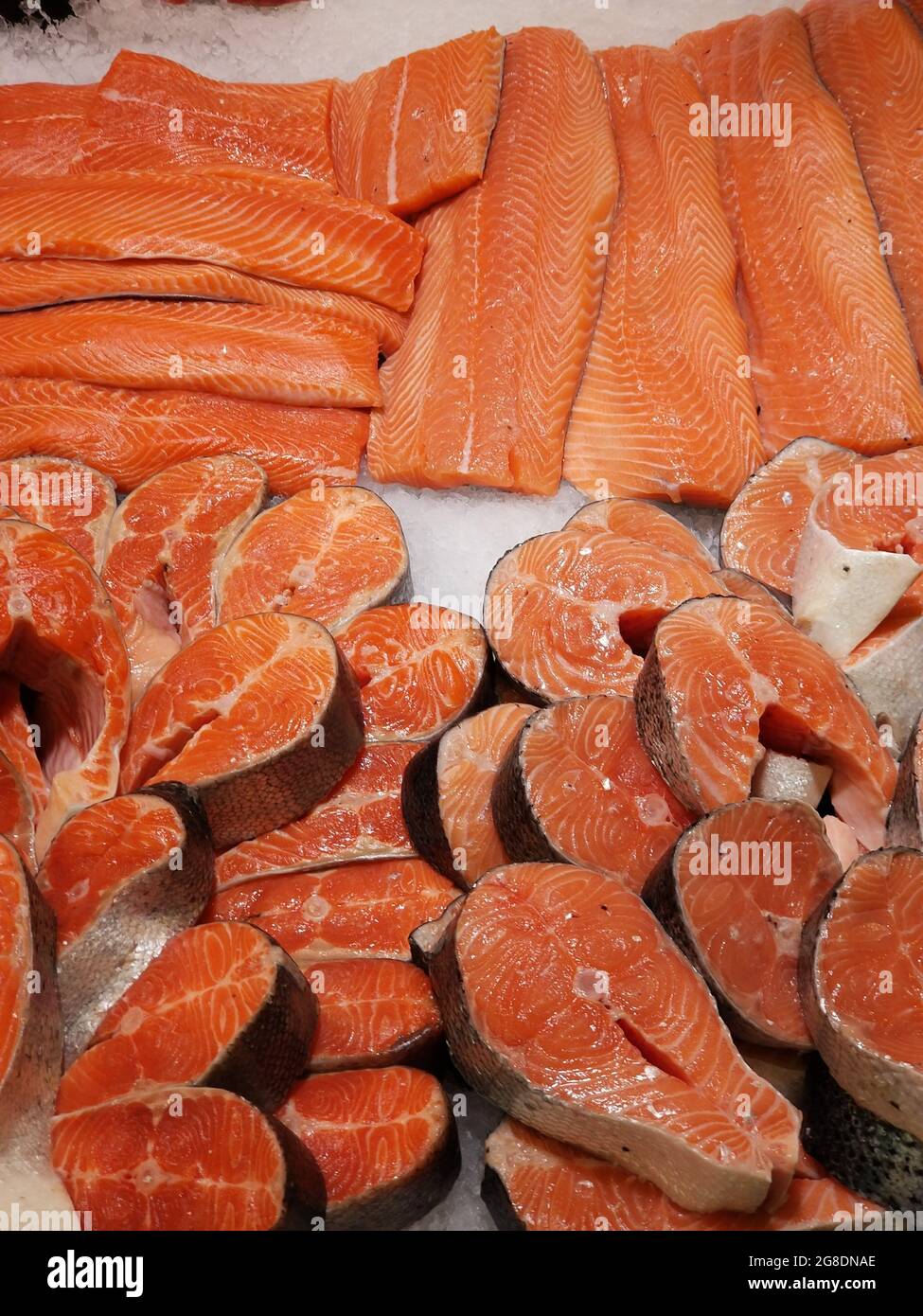 fresh raw red salmon fish steaks and fillet on ice at market counter ...