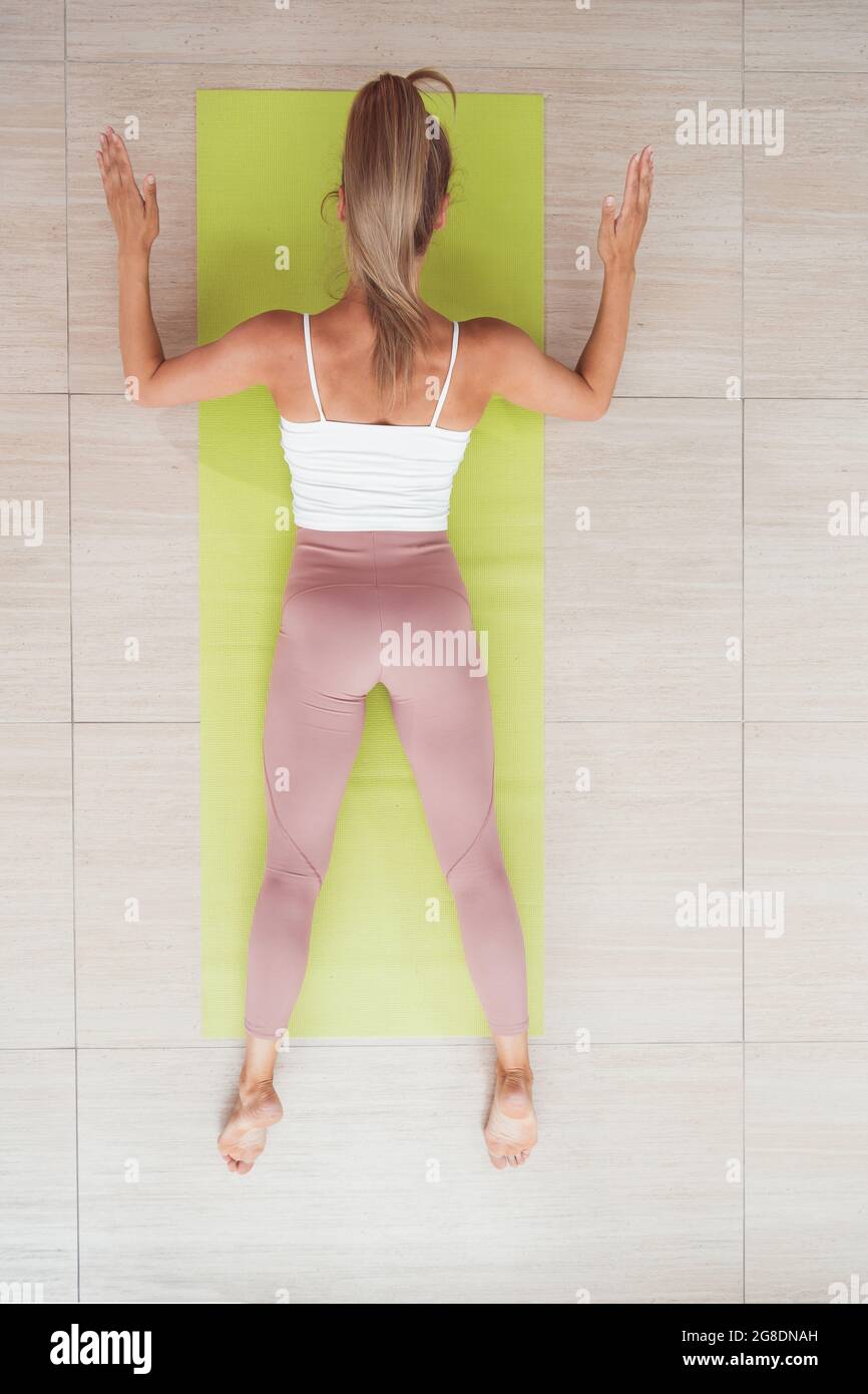 Woman doing back extension exercise on fit ball with online trainer ...