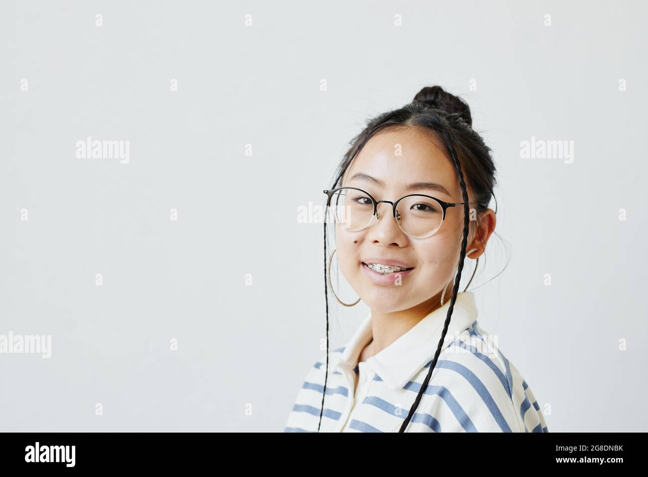 Minimal portrait of Asian teenage girl looking at camera against white ...