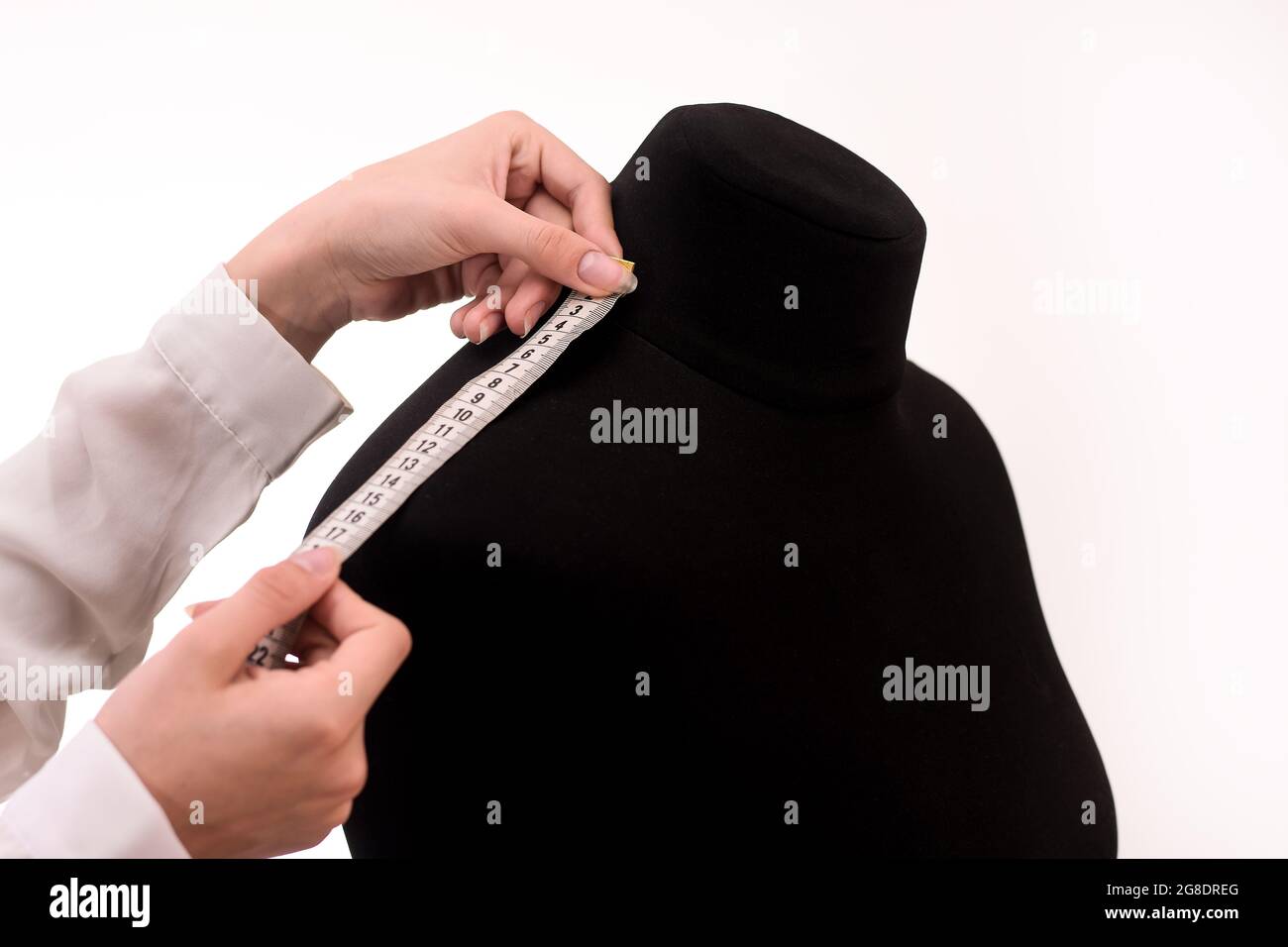 A seamstress measures on a mannequin with a measuring tape Stock Photo ...
