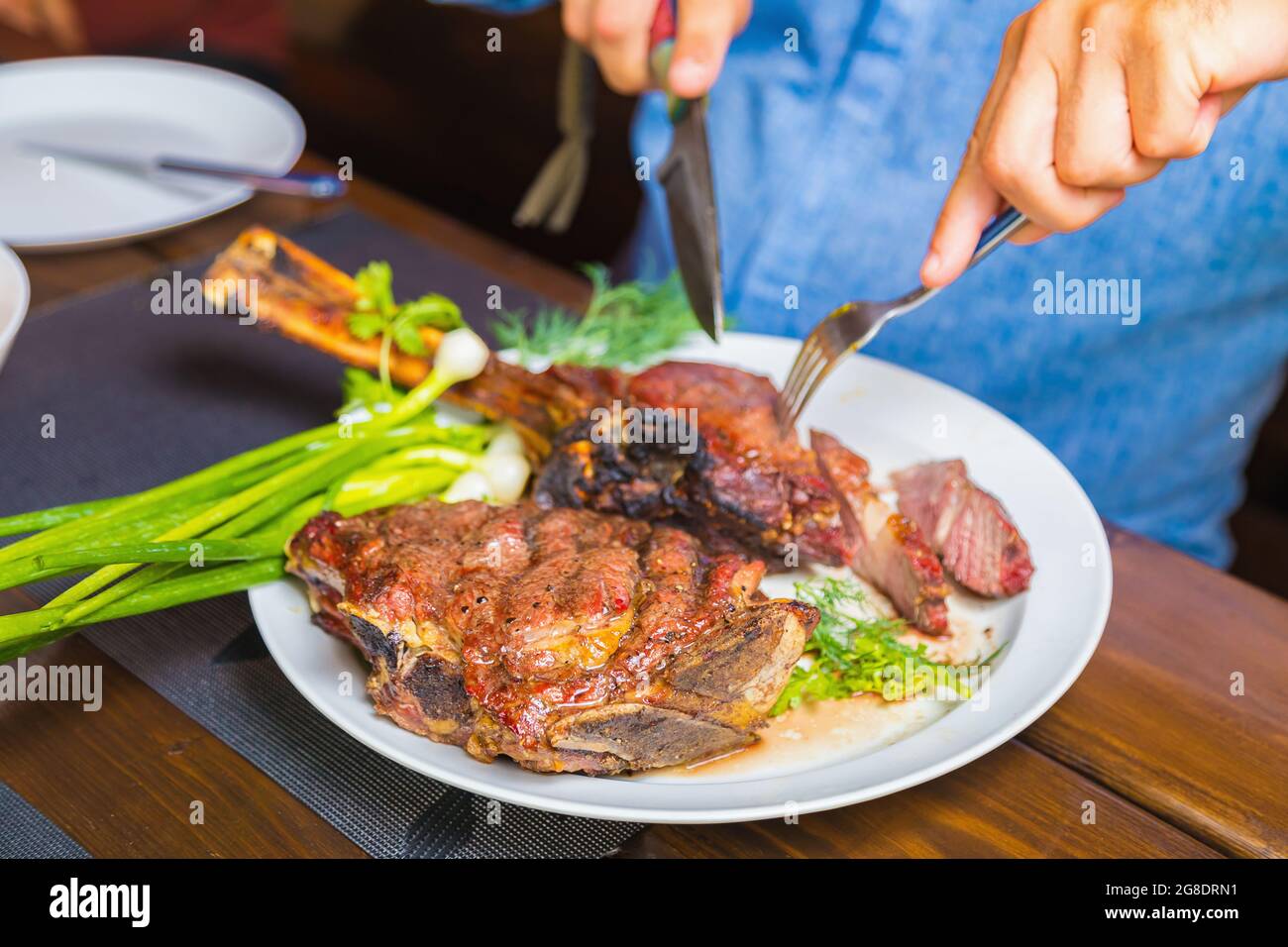 A man cuts cooked fried meat in a plate. Oven-roasted meat for dinner ...