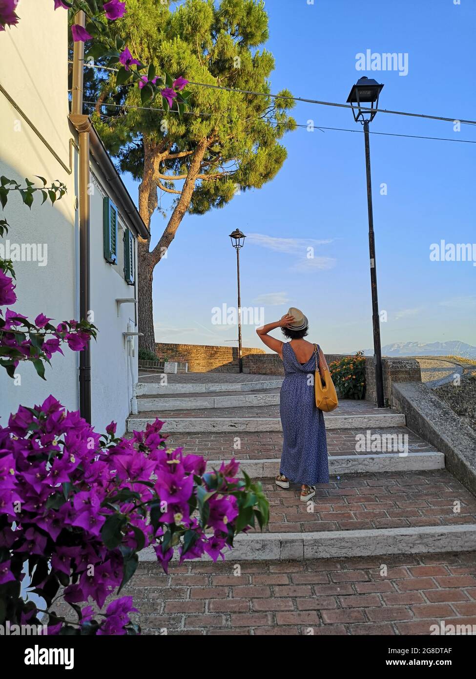 Back view of a female tourist walking on the narrow streets of Spoltore ...