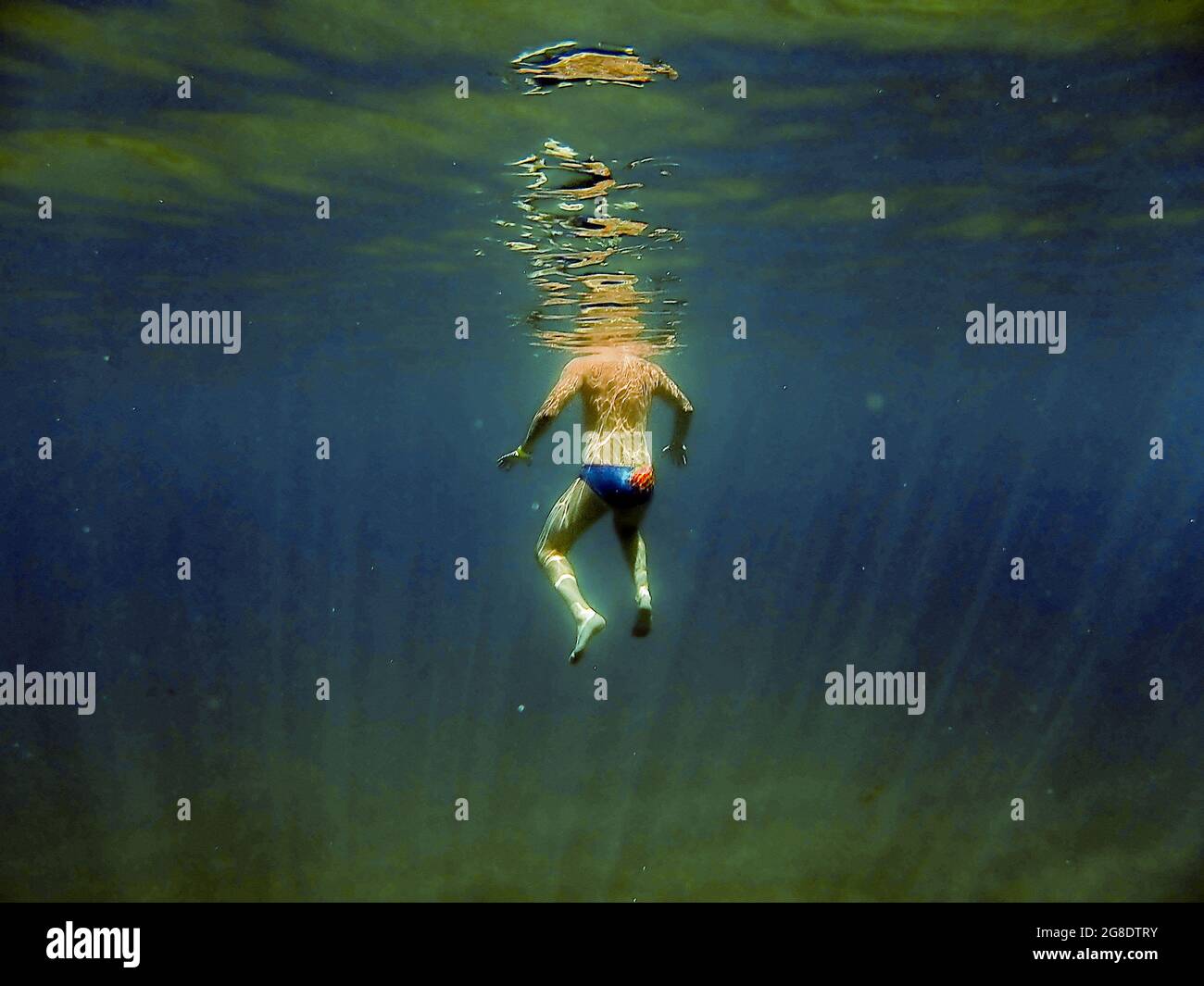 An open-water swimmer taking a moment of rest is seen under the waters ...