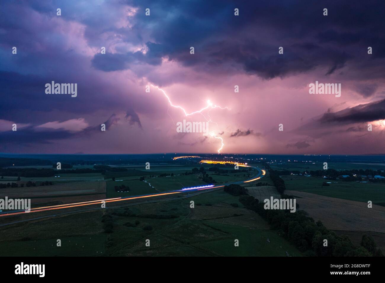 Heavy storm over express road and fields, dark clouds and lightning in ...