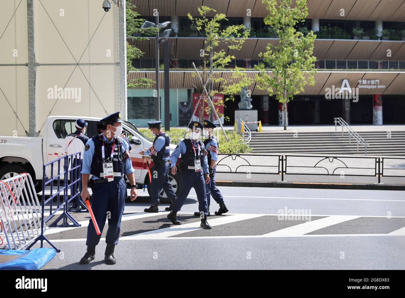 Police officers control a Tokyo 2020 branded pick-up at a check point ...