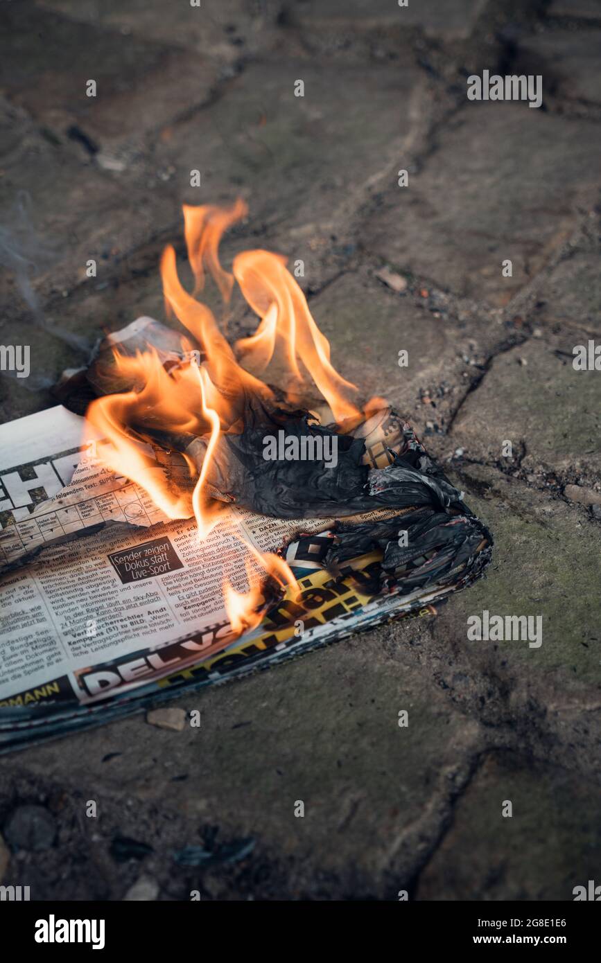 Vertical shot of a burning newspaper on the paving stone ground Stock ...