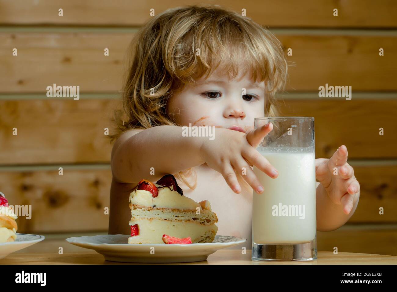 Cute baby boy child eating tasty pie or cake with red strawberry fruit ...