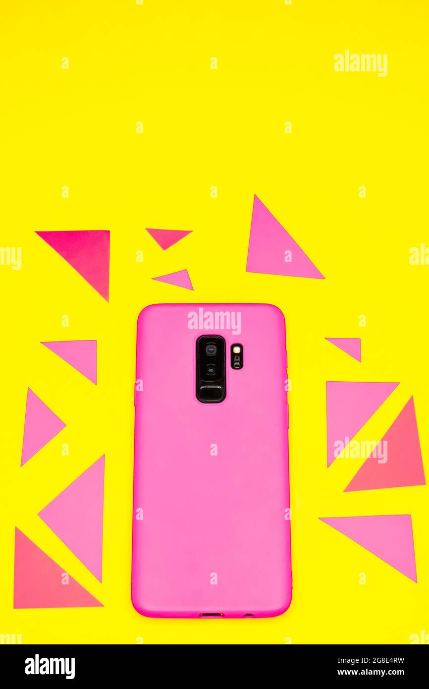 Pink phone on the pink and yellow background with paper triangles Stock ...