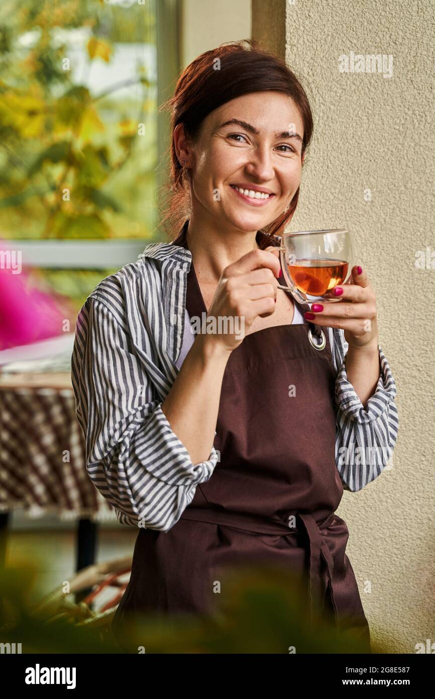 Happy female person drinking tea on loggia Stock Photo - Alamy