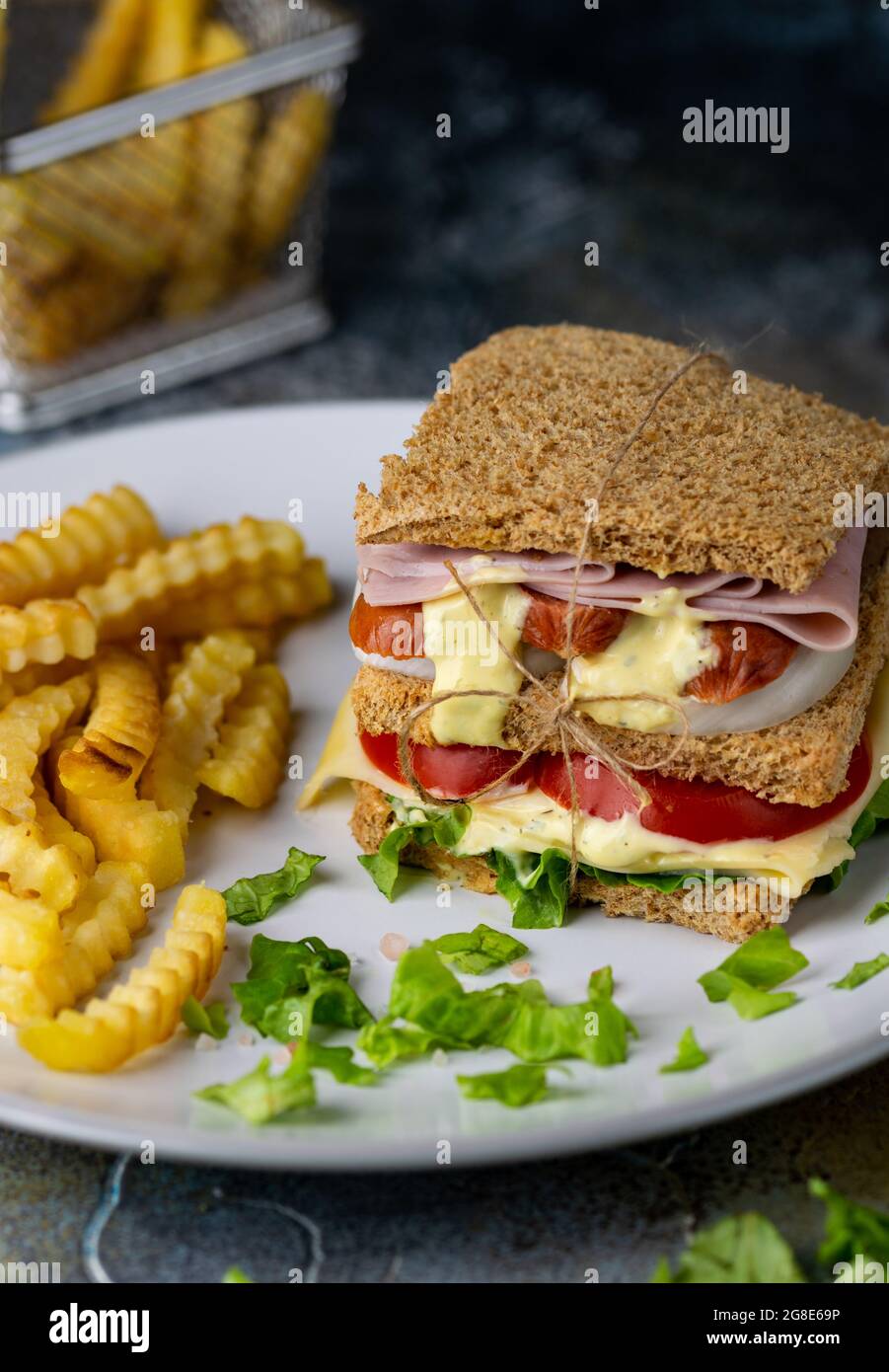 Delicious and tasty clubhouse sandwich and fries with green herbs on a ...