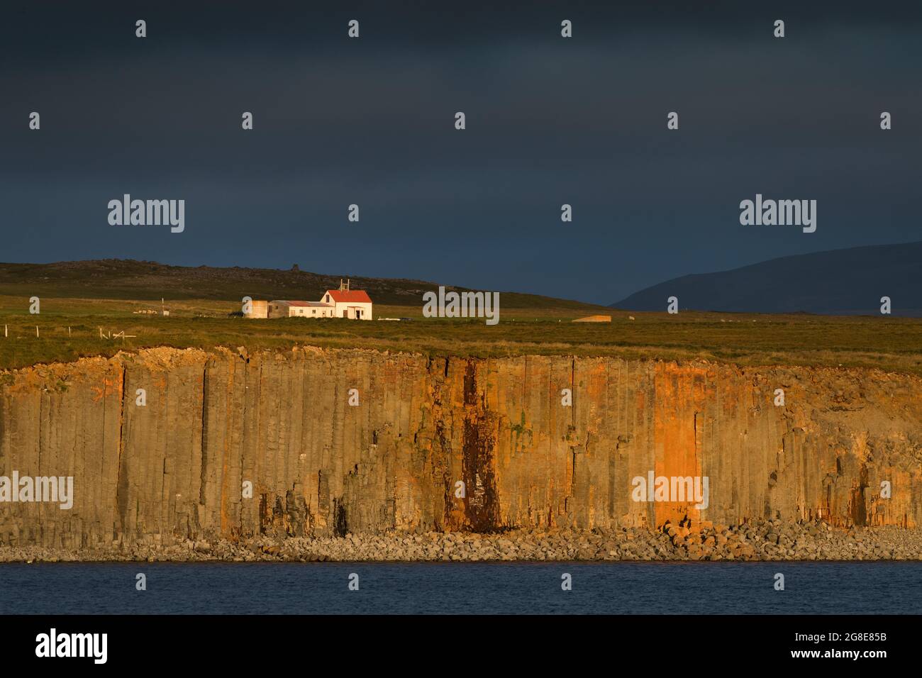 Farm and basalt cliff in the evening light, Kalfshamarsvik, Skagi ...