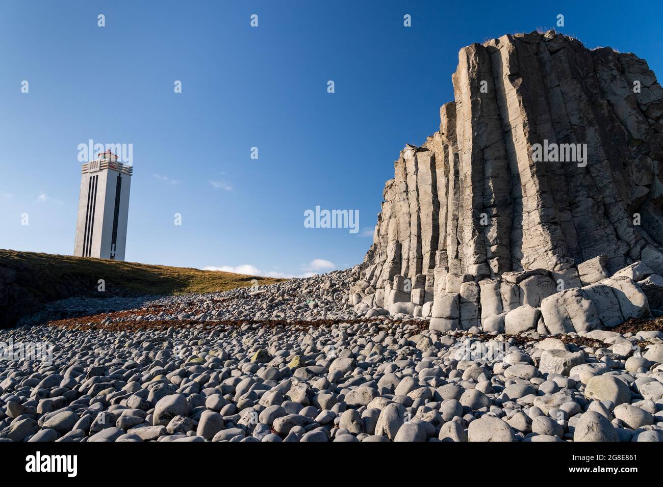Basalt cliff, beach with rounded stones and lighthouse, Kalfshamarsvik ...