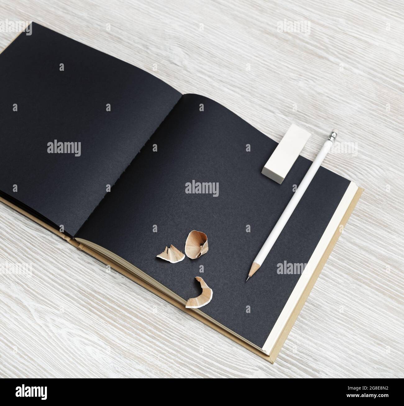 Photo of blank black notebook, pencil and eraser on light wooden ...