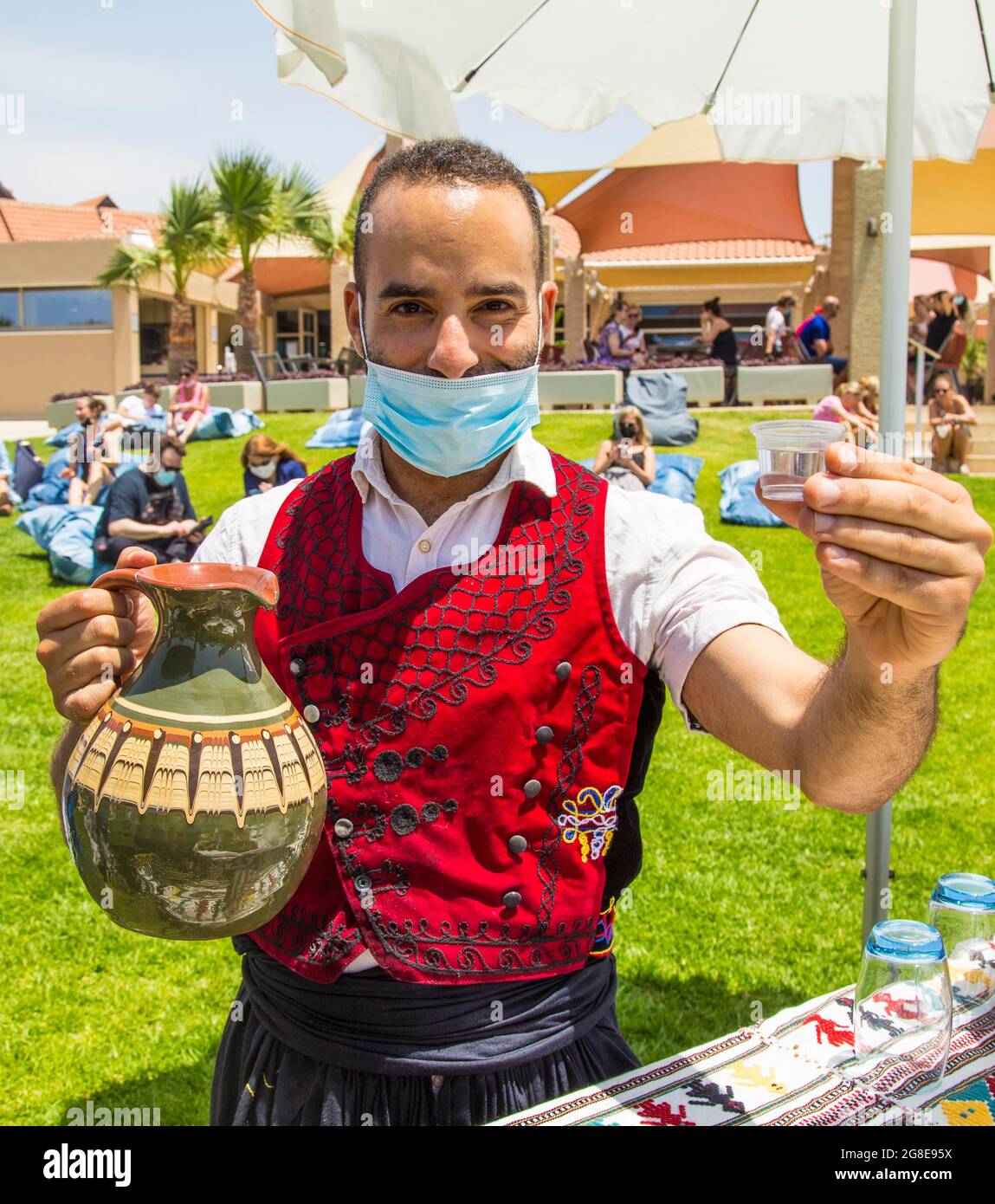 Employee with mask offers typical Cypriot liquor Zivania, Robinson Club ...