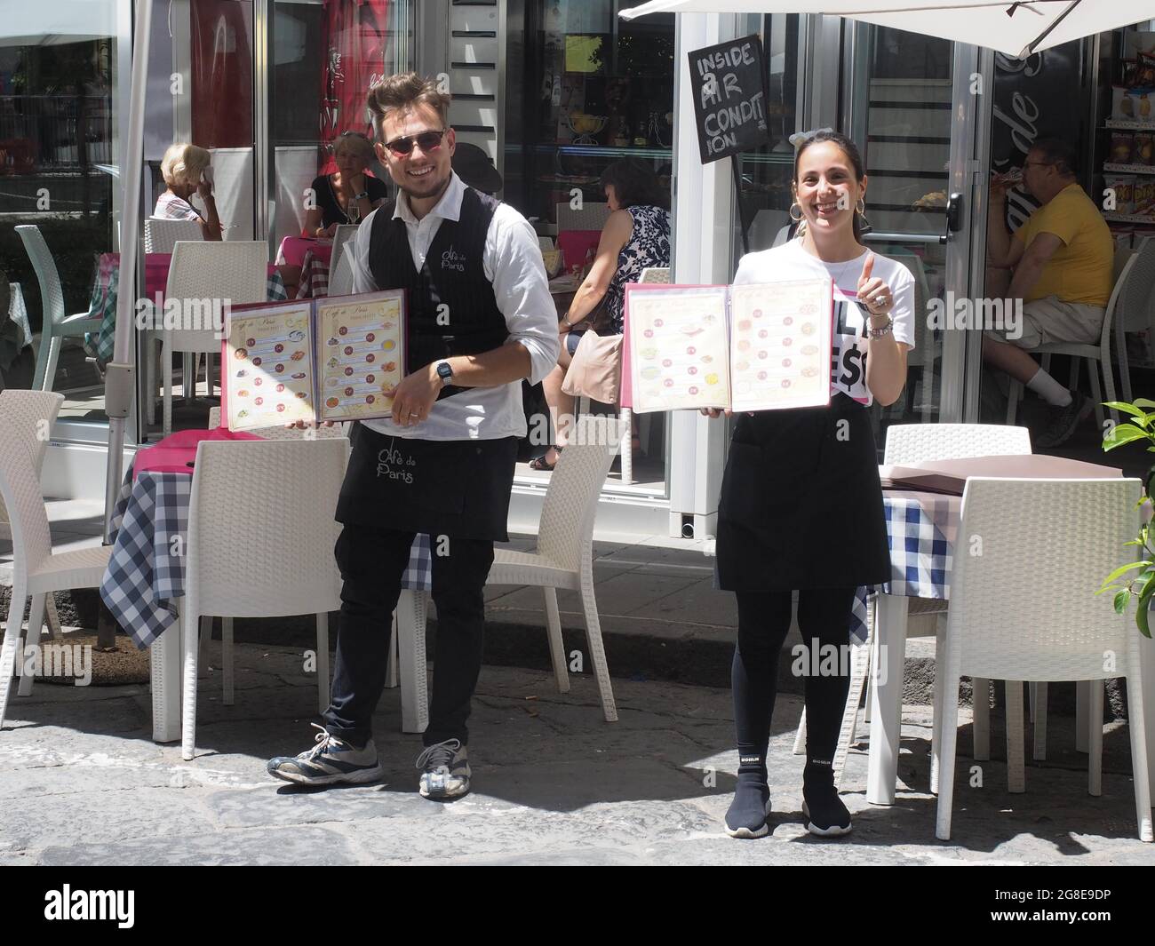 Waitress and waiter showing menu in front of an ice cream cafe ...