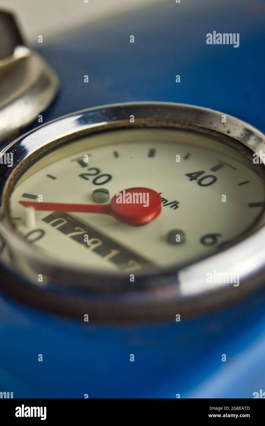 Closeup shot of an old speedometer with a red needle pointing low speed ...