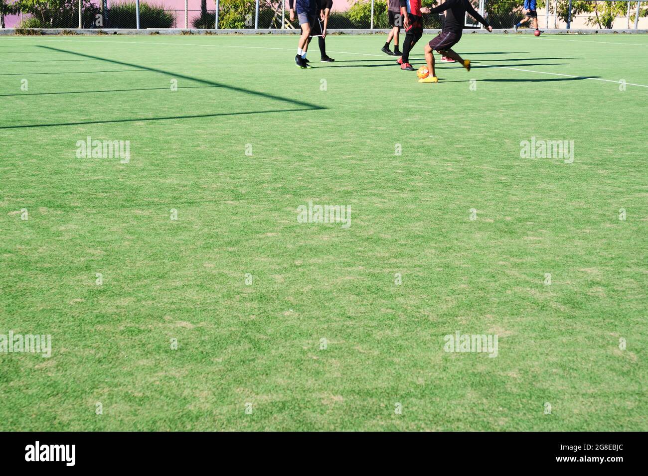 Synthetic soccer field seen through a net. The net and the shadows it ...