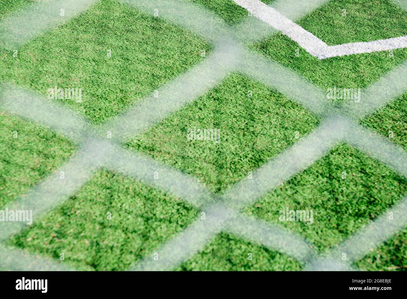 Synthetic soccer field seen through a net. The net and the shadows it ...