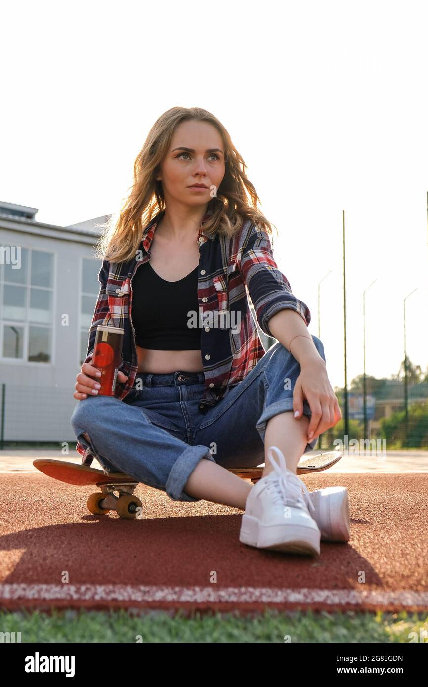 Young millennial woman hippie sitting on skateboard. Summer Skate ...