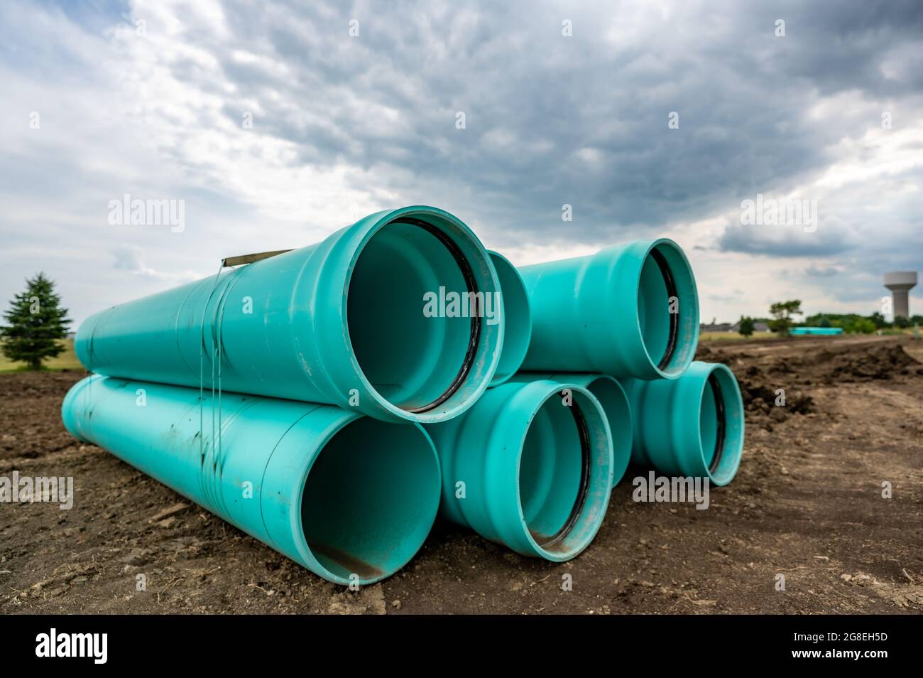 Stacked water main pipe with bell fitting next to an exposed trench for ...