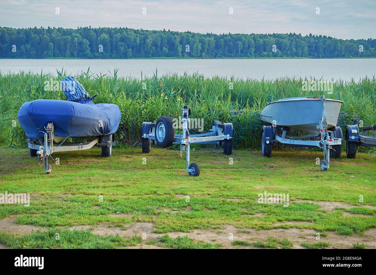 An inflatable boat with a motor in a cover and a plastic boat on carts ...