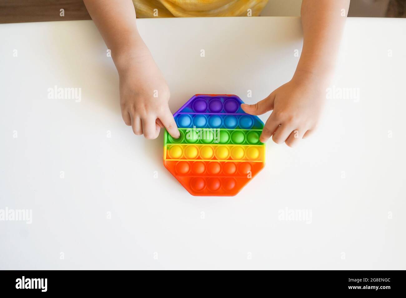 Pop it fidget in kid's hands. Colorful toy push pop it. Top view of ...