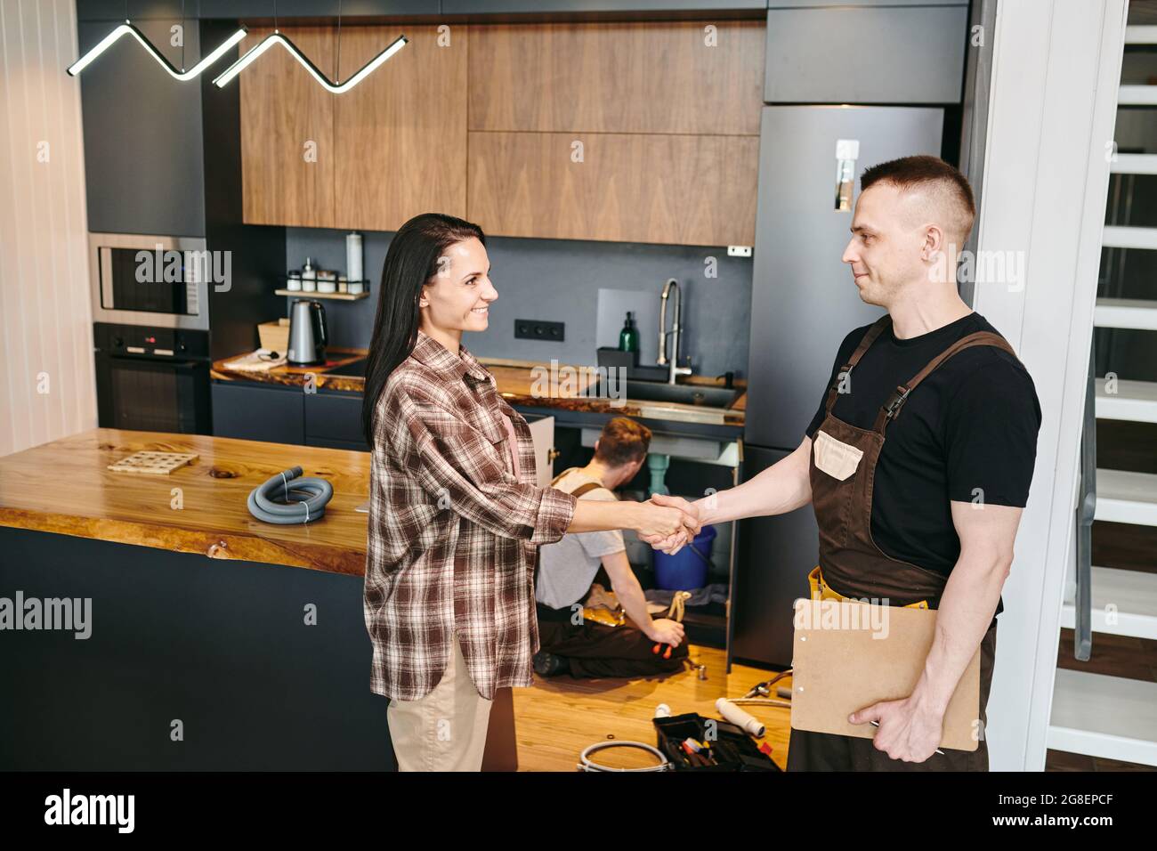 Happy young woman shaking hand of plumber after repairing work Stock ...
