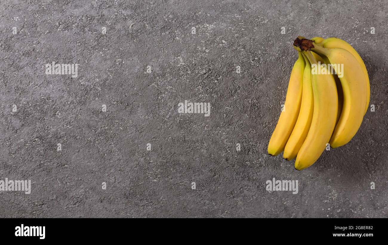 branch of ripe bananas on gray concrete with copy space. closeup Stock ...