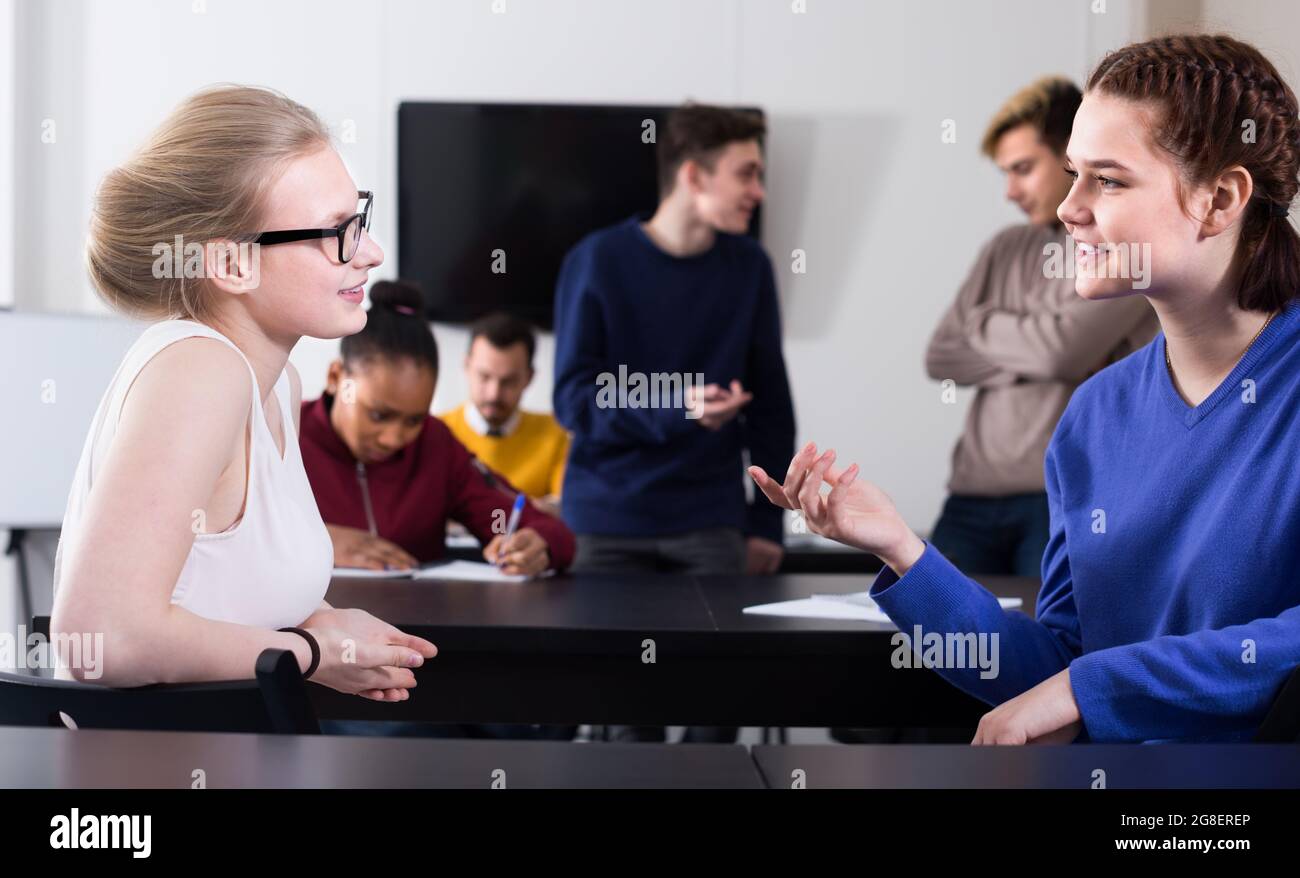 positive classmates having animated talks at break between classes ...