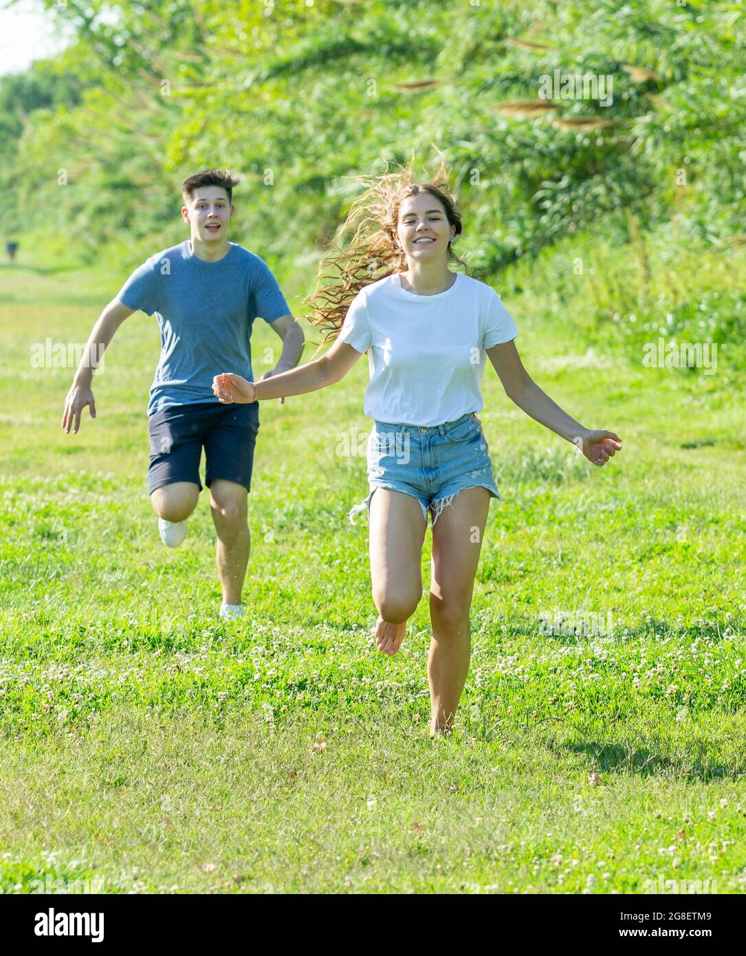 Laughing teenagers playing outdoors funning at grass on day Stock Photo ...