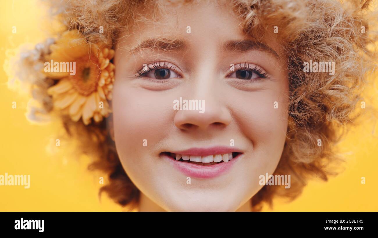 Beautiful young girl with curly hair and orange gerbera daisy flower on ...