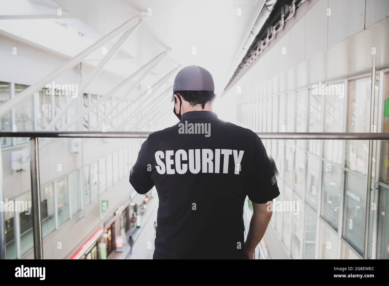 Male security guard with a black t-shirt and cap standing inside the ...