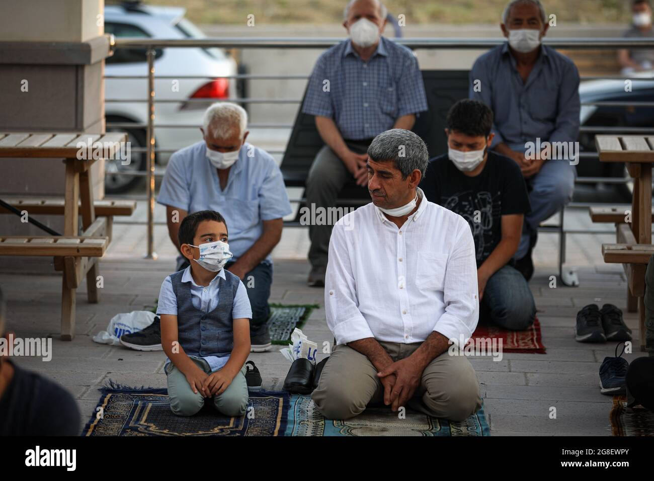 A father and son wearing face masks pray on Eid al-Adha at Atayurt ...