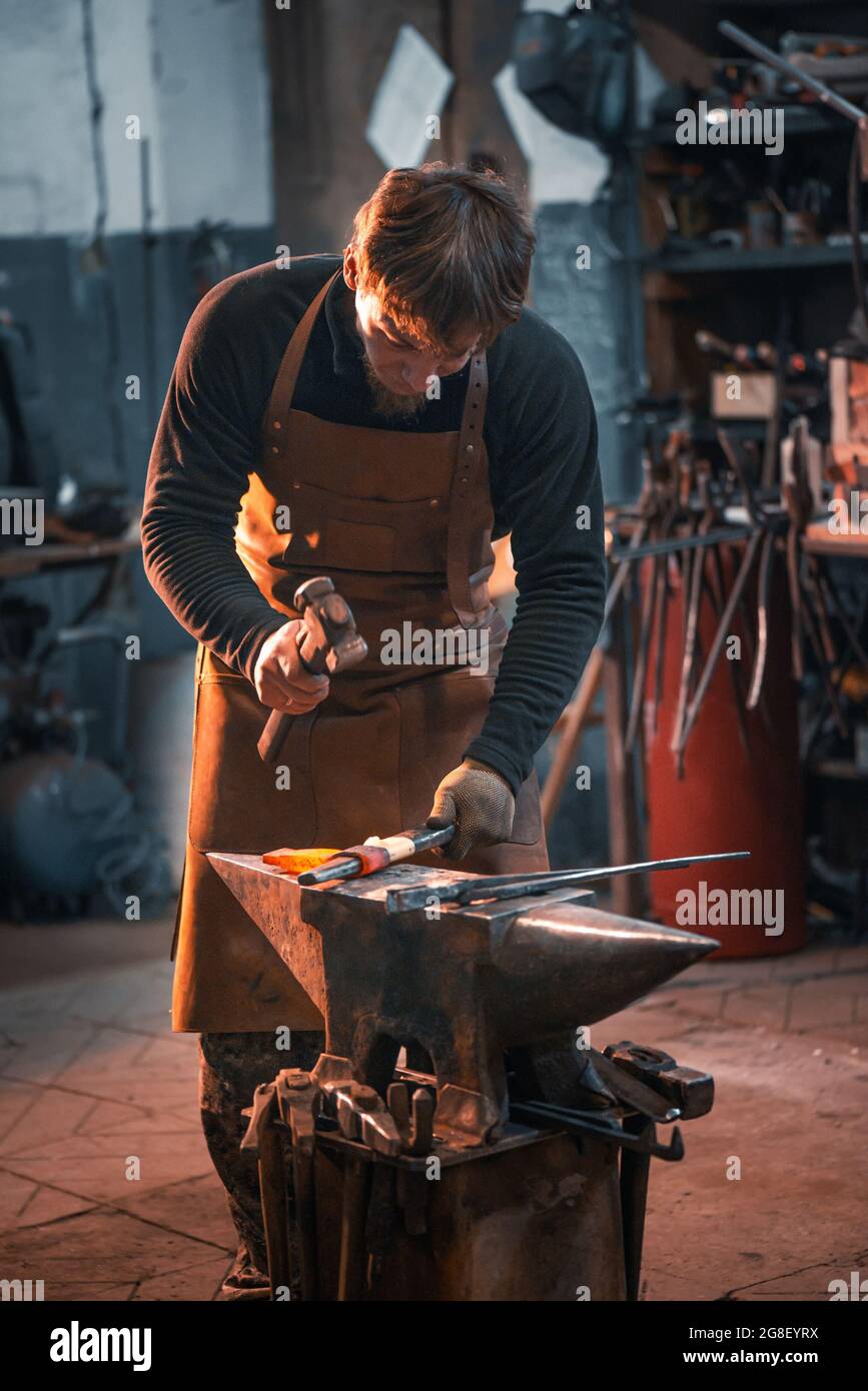 Blacksmith is working on an anvil, forging a red-hot metal blank Stock ...