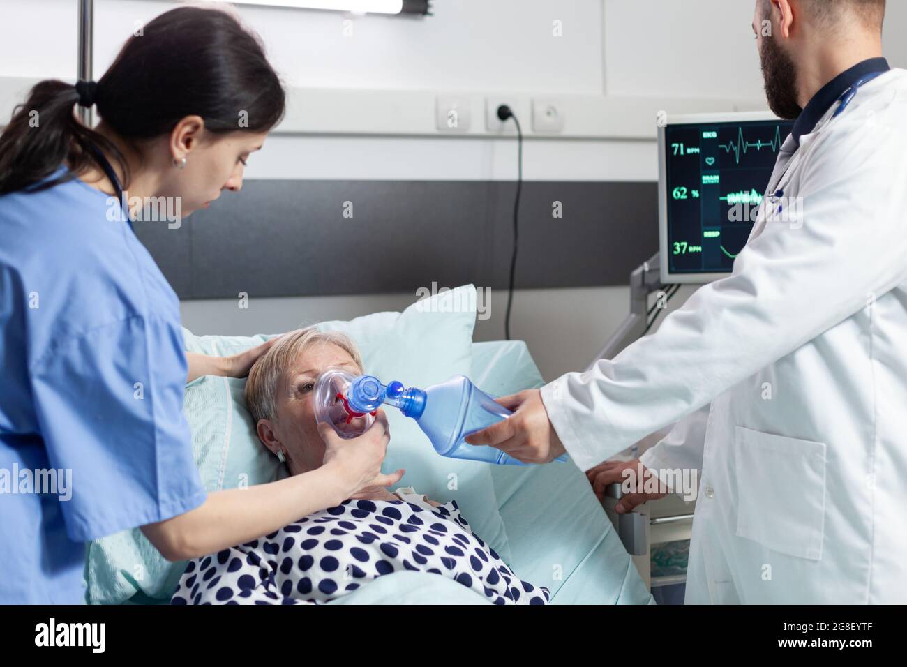 Medical team helping senior woman patient laying in hospital bed, to ...