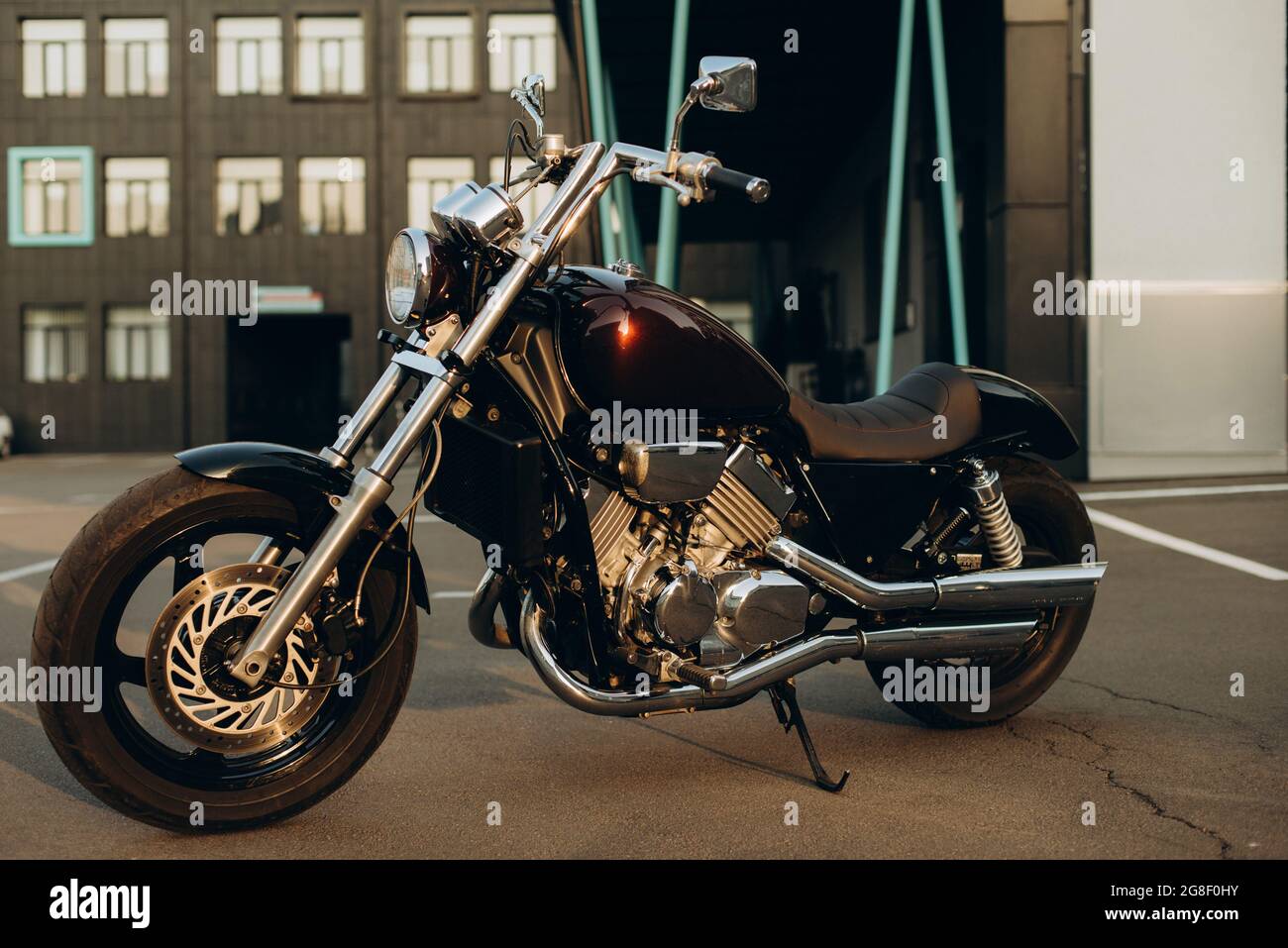 A motorcycle in a parking lot in the warm light of a sunset. Stylish ...