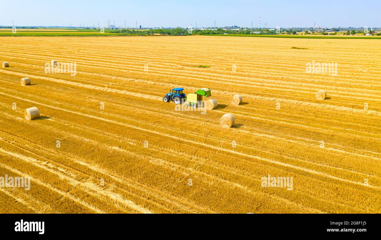 Above top view on tractor as pulling round baler, machine that rolls up ...