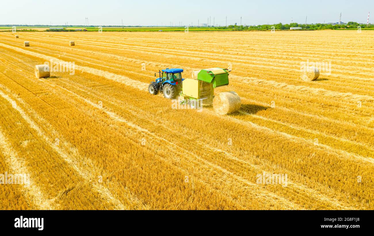 Above top view on tractor as pulling round baler, machine that rolls up ...