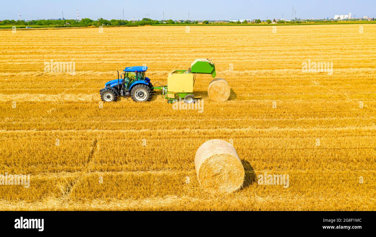 Above top view on tractor as pulling round baler, machine that rolls up ...