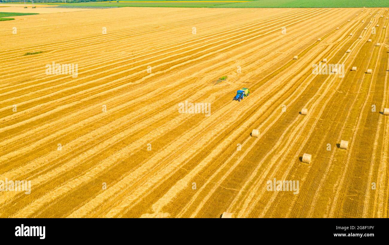 Above top view on tractor as pulling round baler, machine that rolls up ...