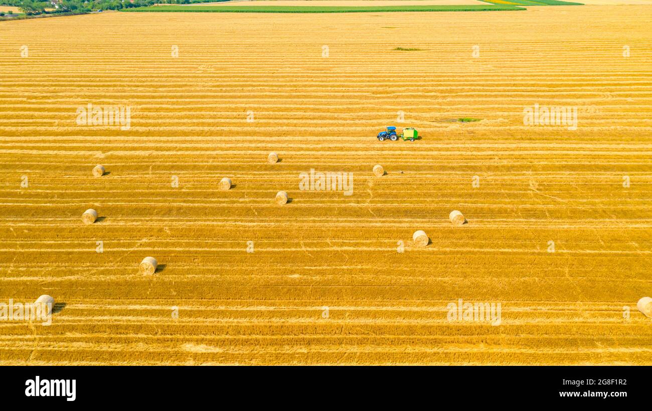 Above top view on tractor as pulling round baler, machine that rolls up ...