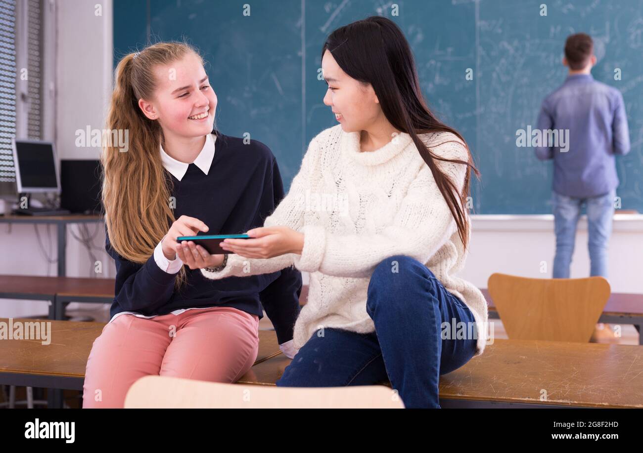 Female students talking and using smartphone during break Stock Photo ...