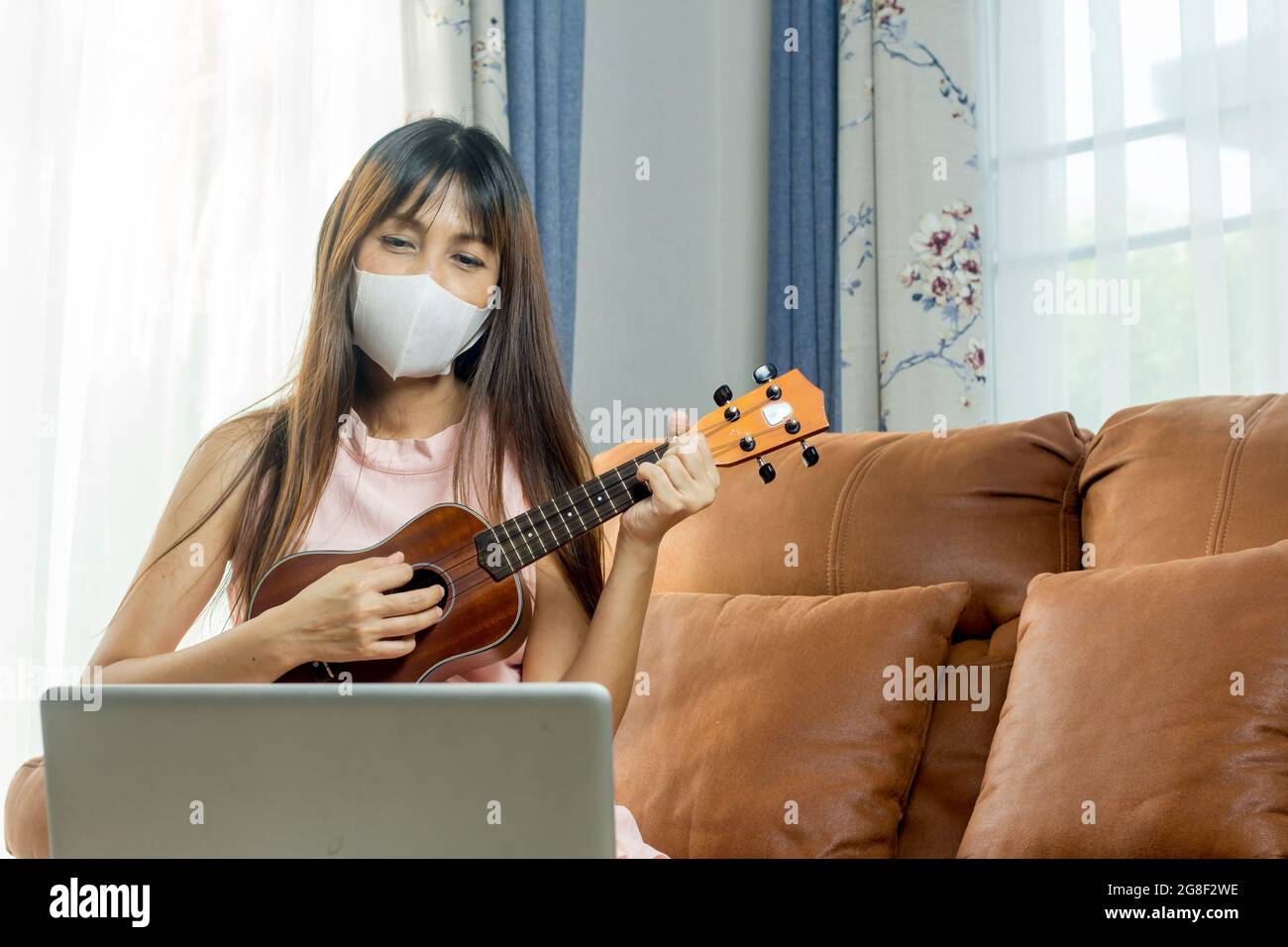 Women wear a mask and learn how to play ukulele from their home laptops ...