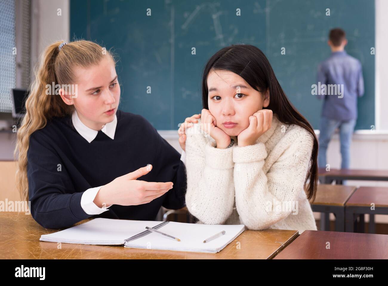 Tired female students during writing notes in classroom Stock Photo - Alamy