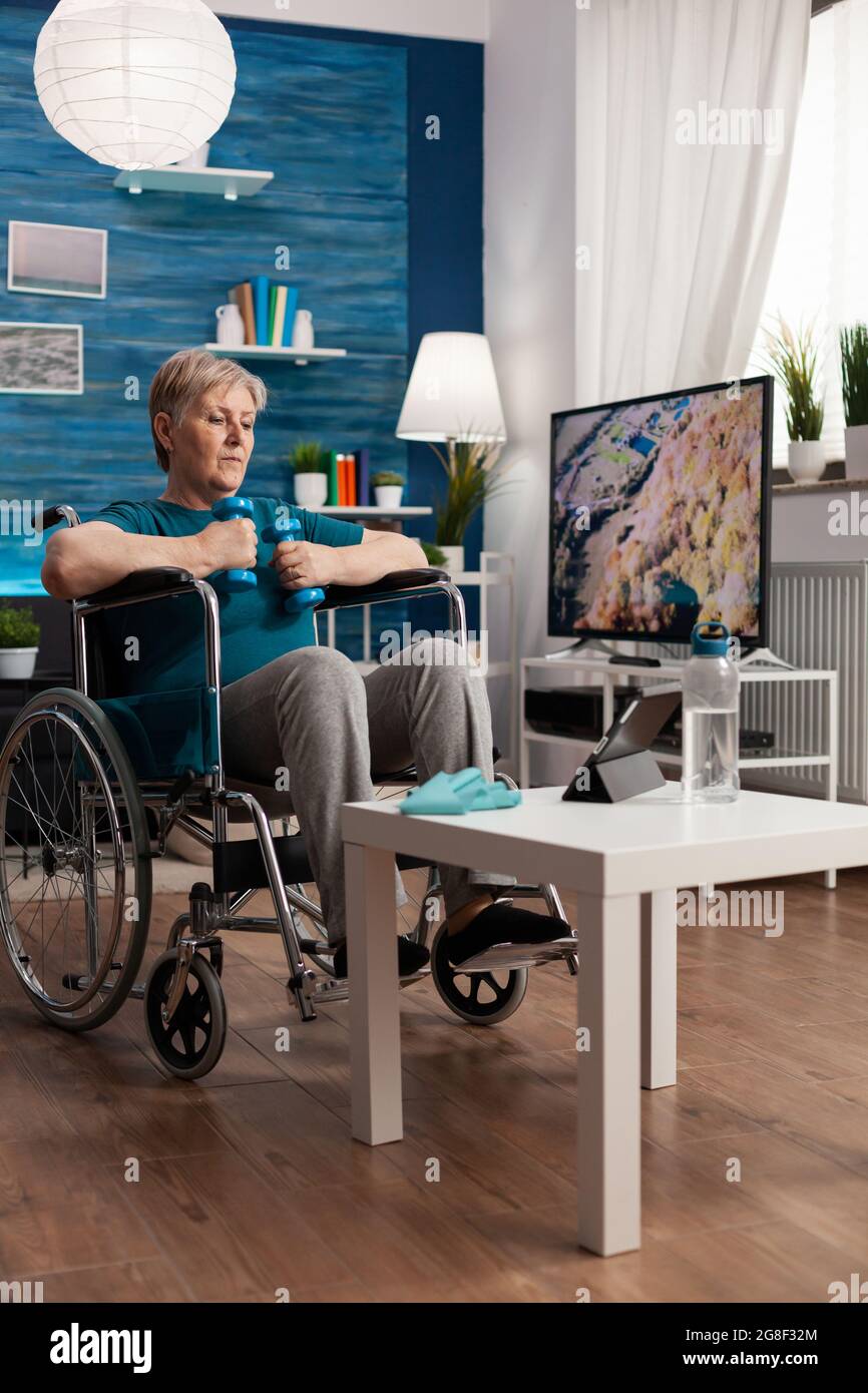 Invalid senior woman in wheelchair training body muscles using ...