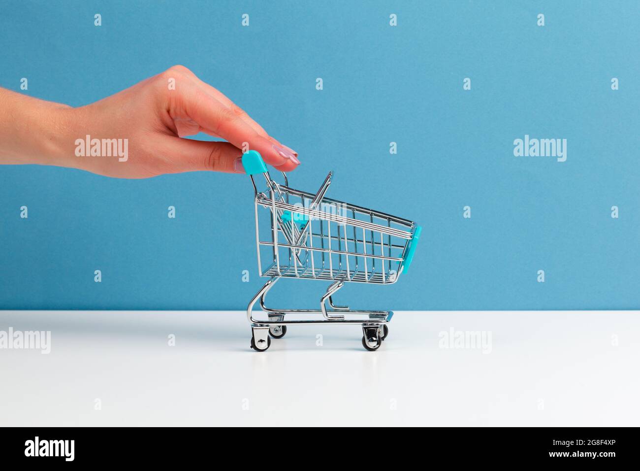 shopping cart trolley on hand on white and blue background. Side view ...