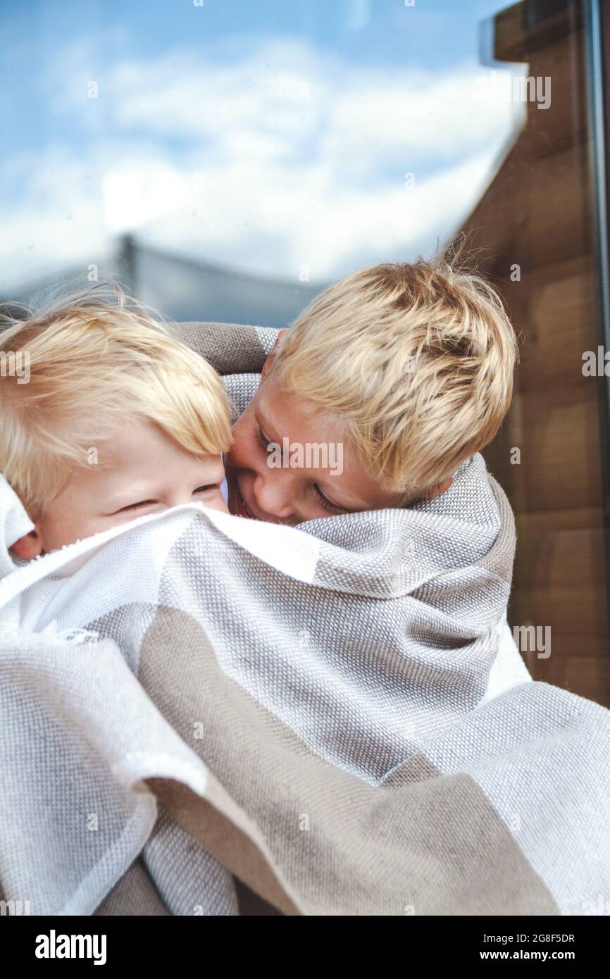 Two brothers hug and have fun together under a warm plaid Stock Photo ...