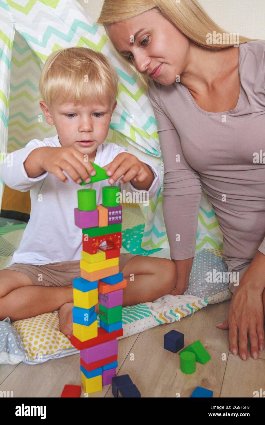Mom and son build a tower together from constructor Stock Photo - Alamy